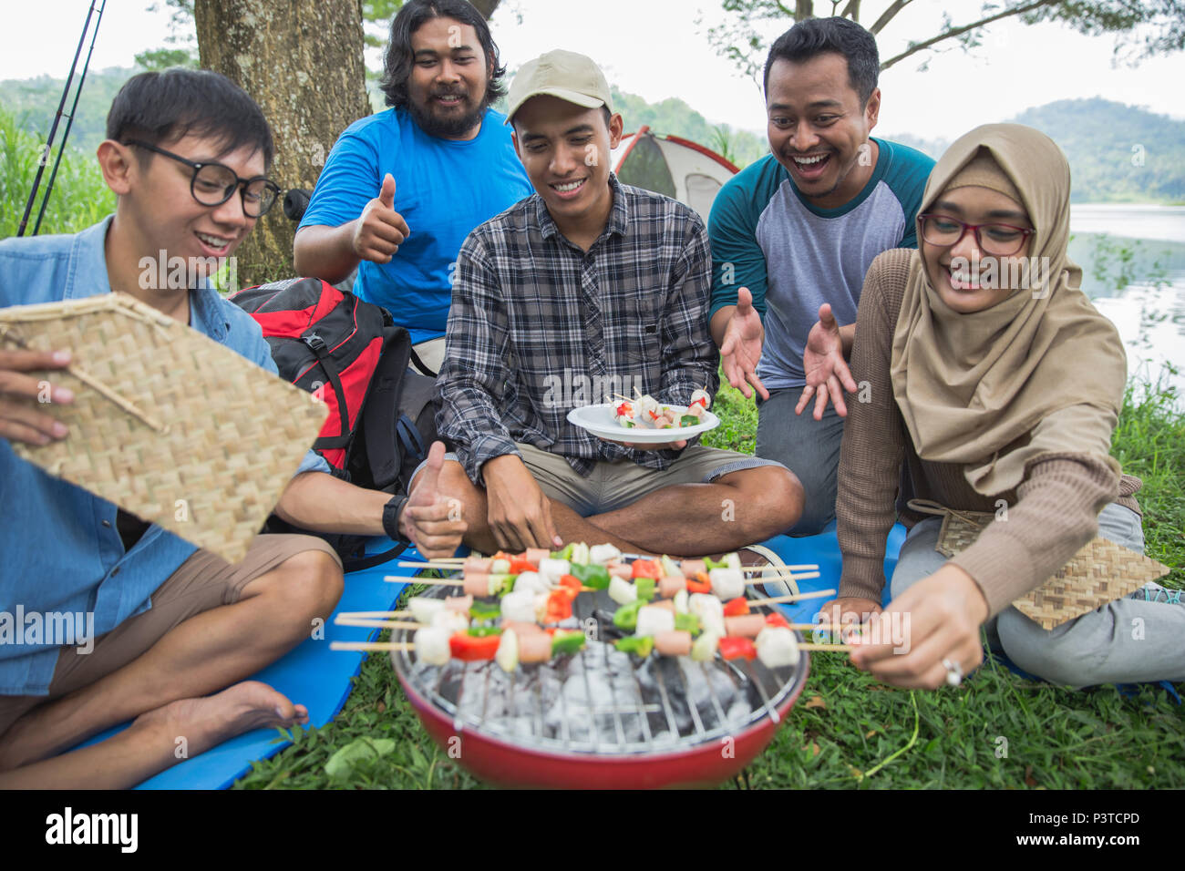 Friends making a barbecue together outdoors Stock Photo - Alamy