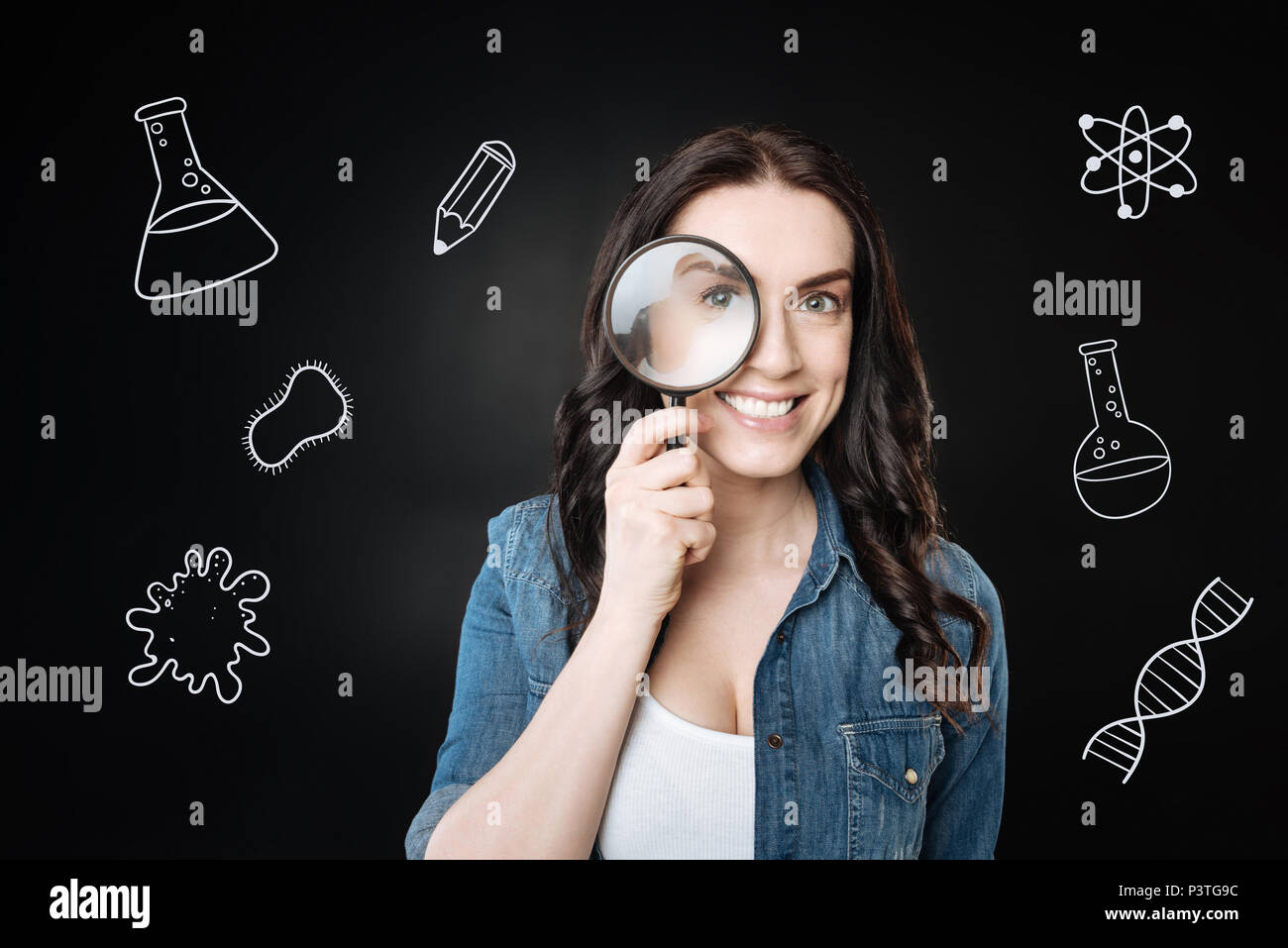 Excited chemistry teacher putting a magnifying glass to her face and ...