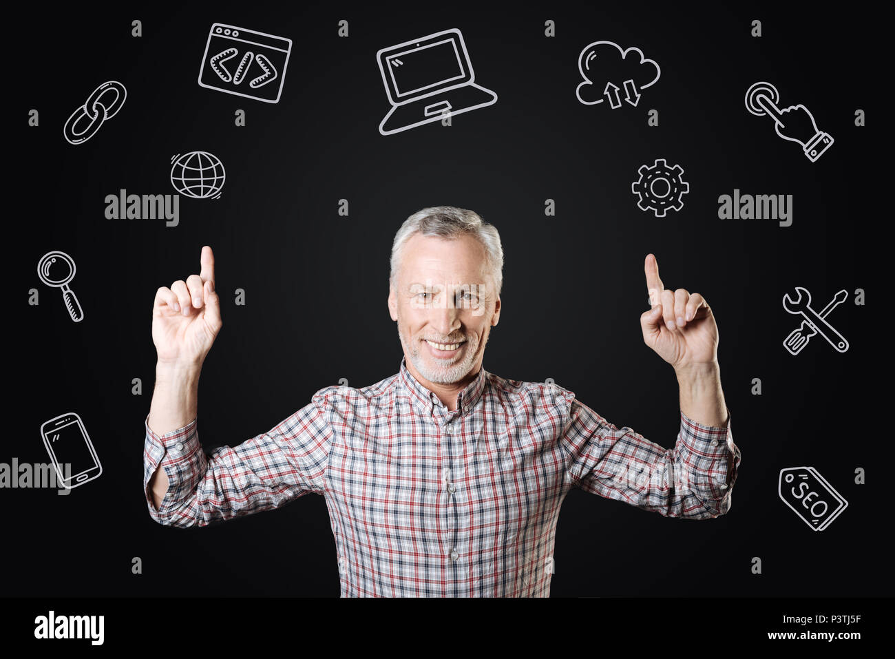 Positive programmer smiling and looking happy while pointing his fingers up Stock Photo - Alamy