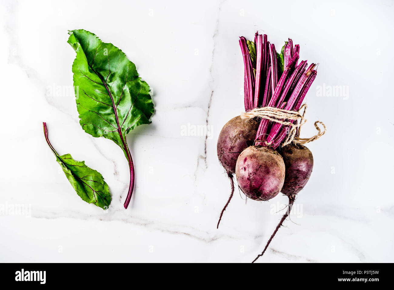 Fresh raw beetroot with green leaves, white marble background copy ...