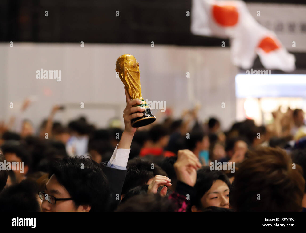 Tokyo, Japan. 19th June, 2018. A man raises a replica trophy of the ...