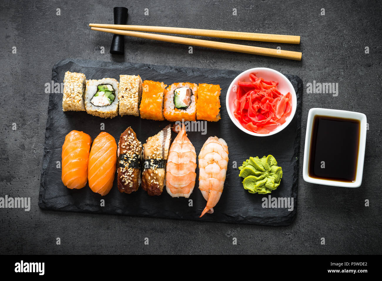 Sushi and sushi roll set on black stone table top view. Traditional ...