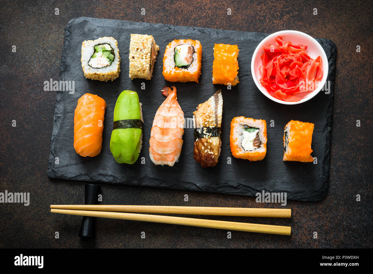 Sushi and sushi roll set on dark stone table top view. Traditional ...