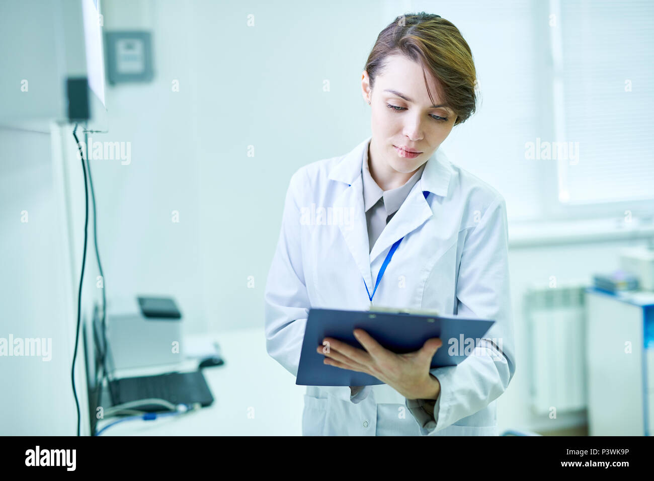 Doctor standing with clipboard and taking notes Stock Photo - Alamy
