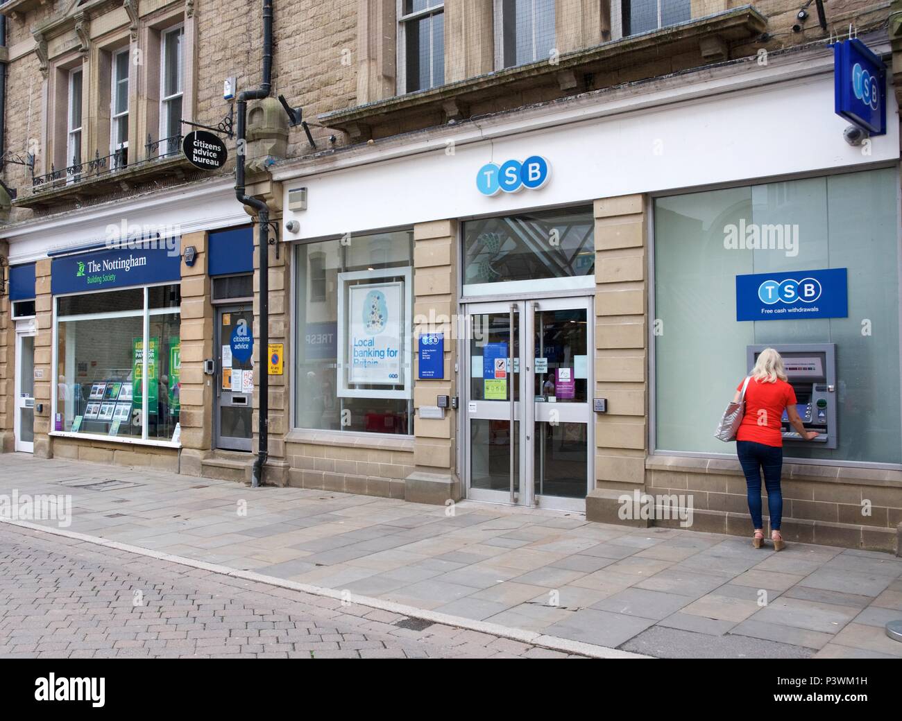 A woman uses the TSB ATM in Buxton, High Peak, Derbyshire, UK Stock ...
