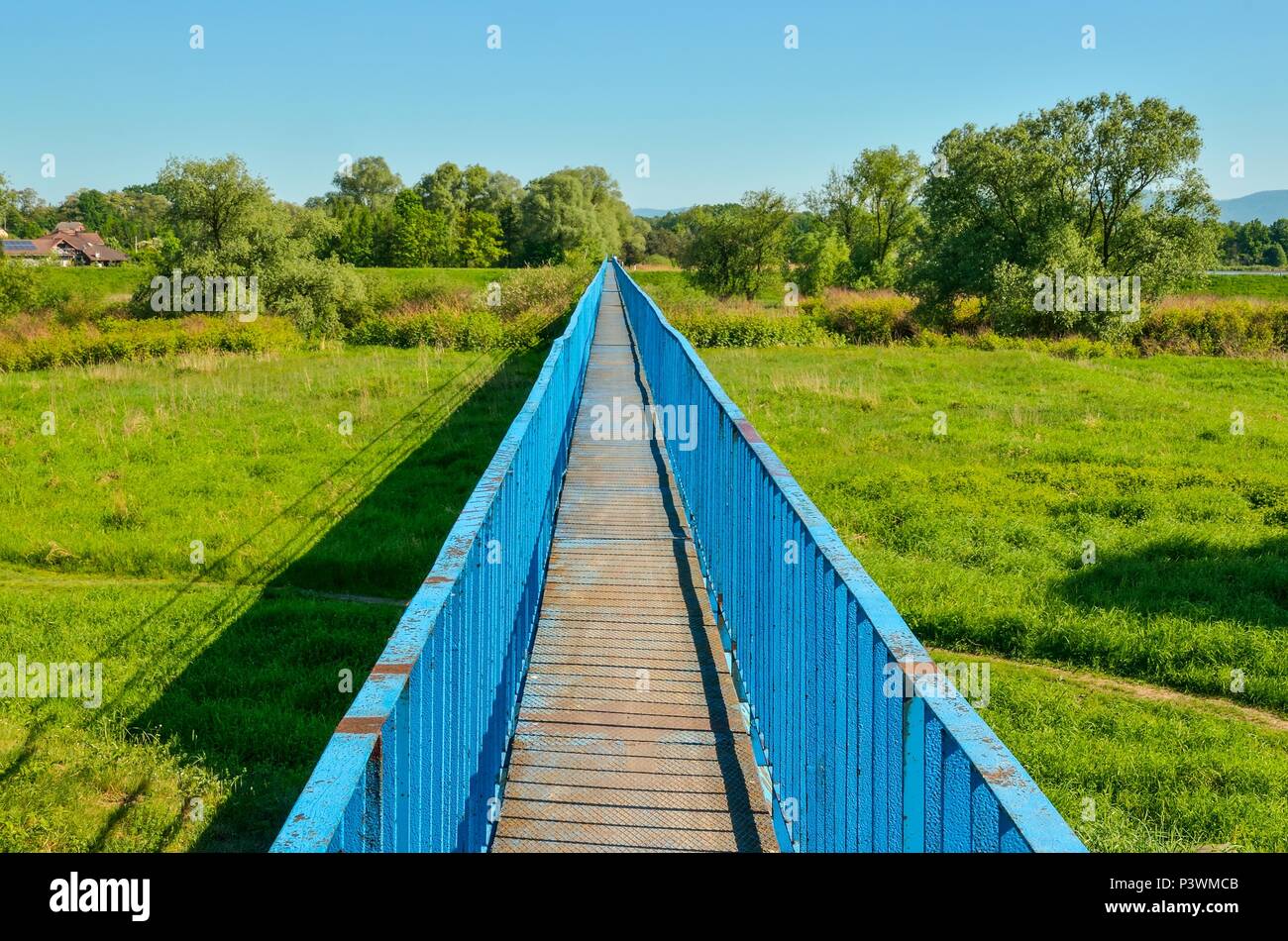 Springtime rural landscape. Metal footbridge over the river in the ...