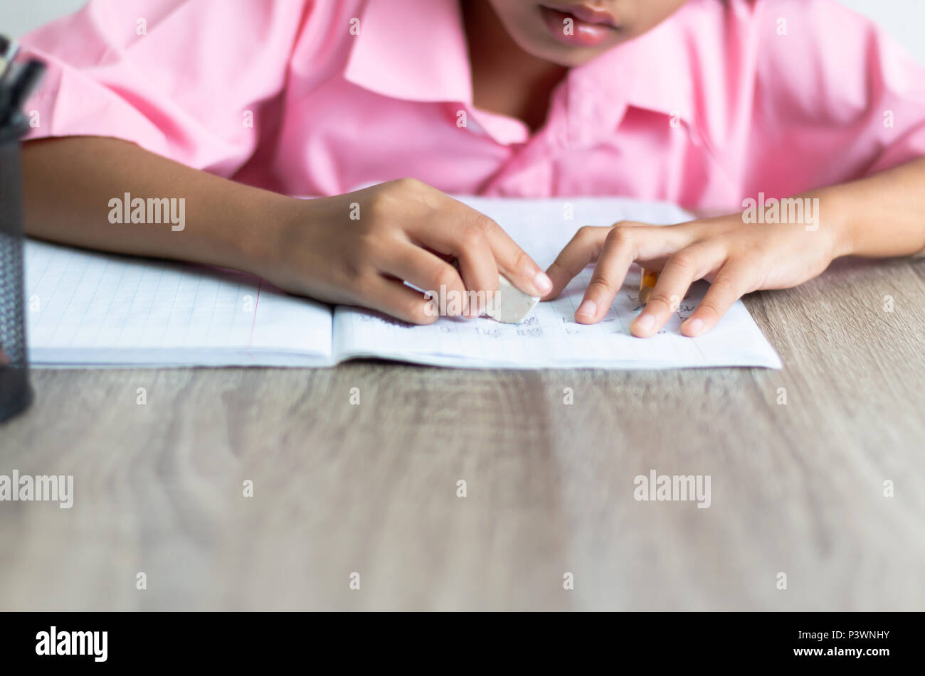 Children use a eraser is deleting words. Close up the little girl is ...