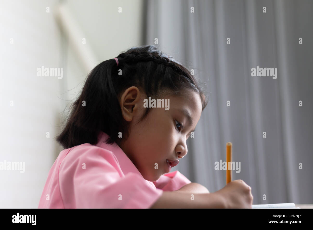 Close up the little girl is doing homework intently. Children use a ...