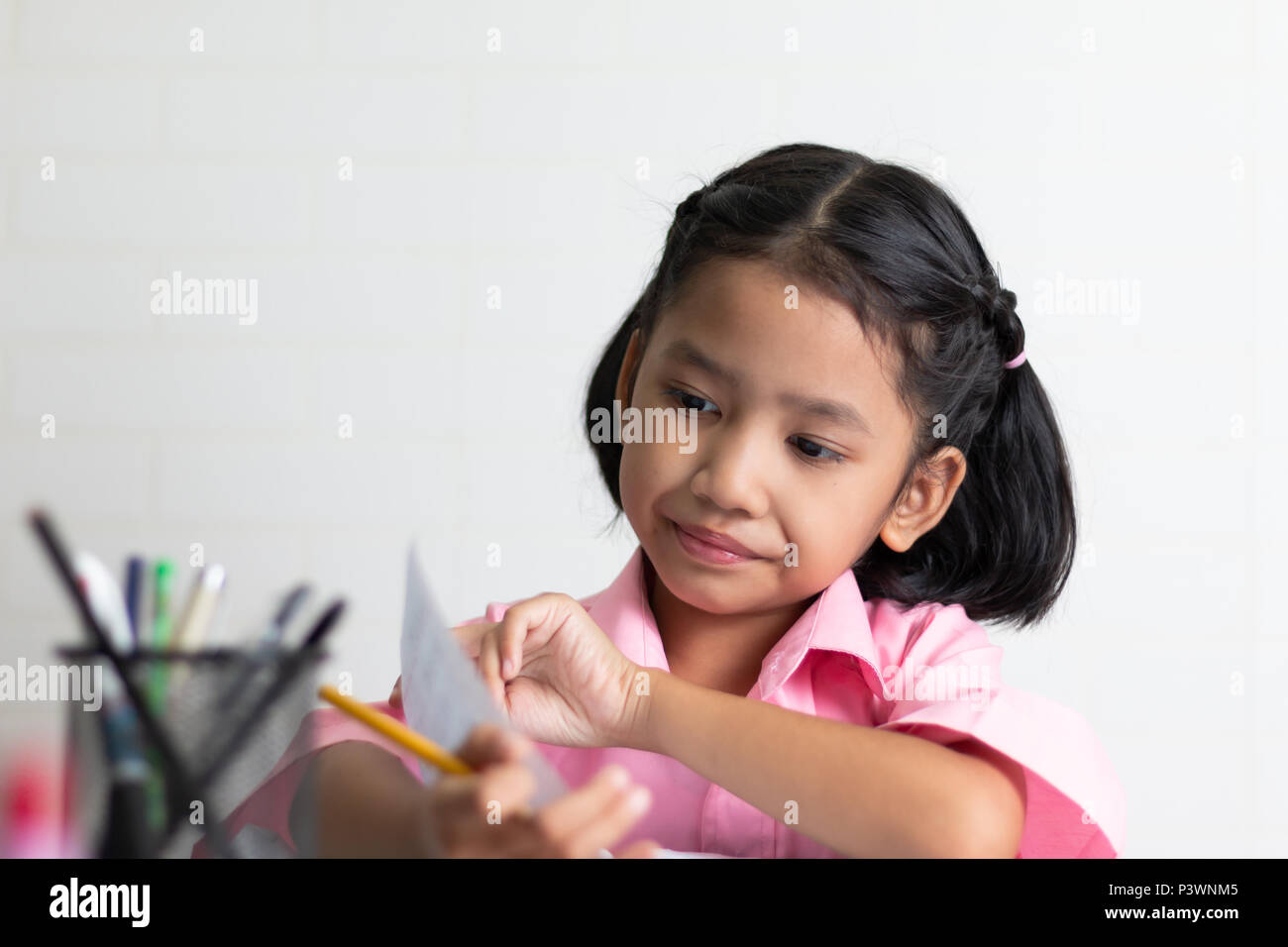 The little girl is doing homework intently. Children use a yellow ...