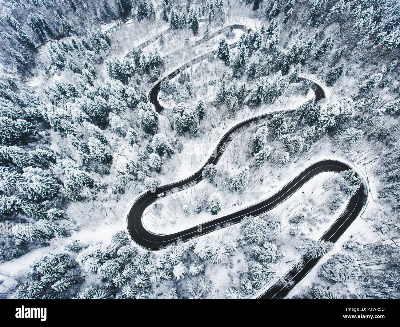 Snowy road in the forest. Extreme winding road high up in the mountains ...