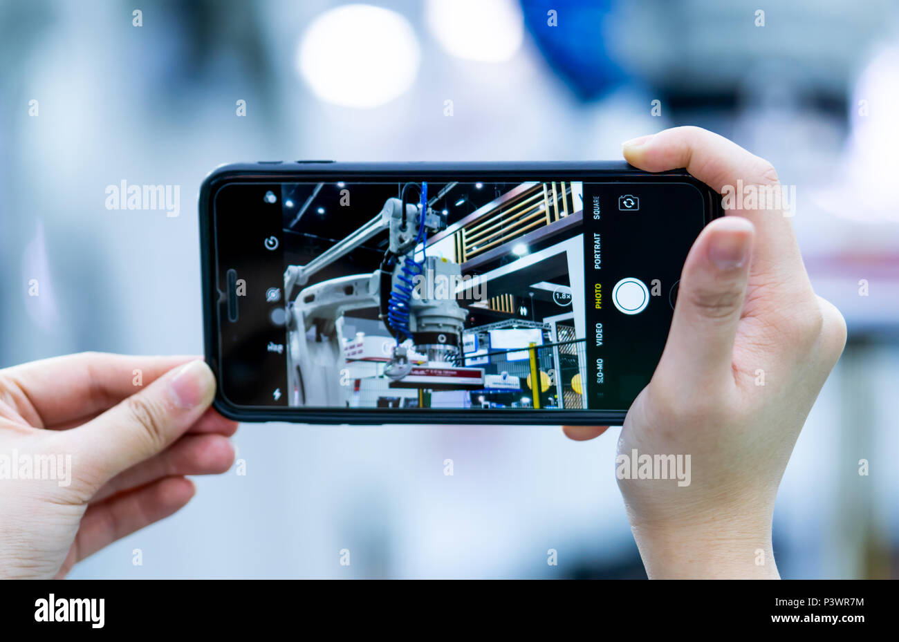 Woman hand use smart phone shoot photo of robot at the industrial expo ...