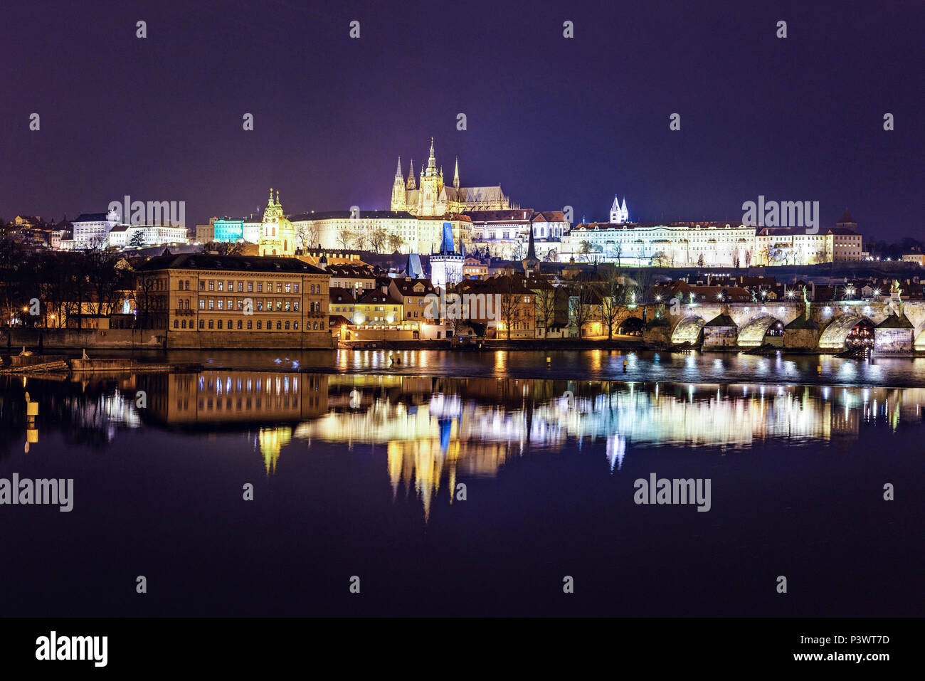 Prague Castle and Charles Bridge at night with lights glowing and ...