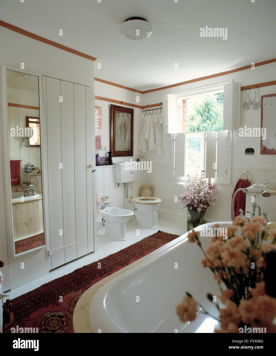 Old fashioned white country bathroom with roll-top bath and window ith ...
