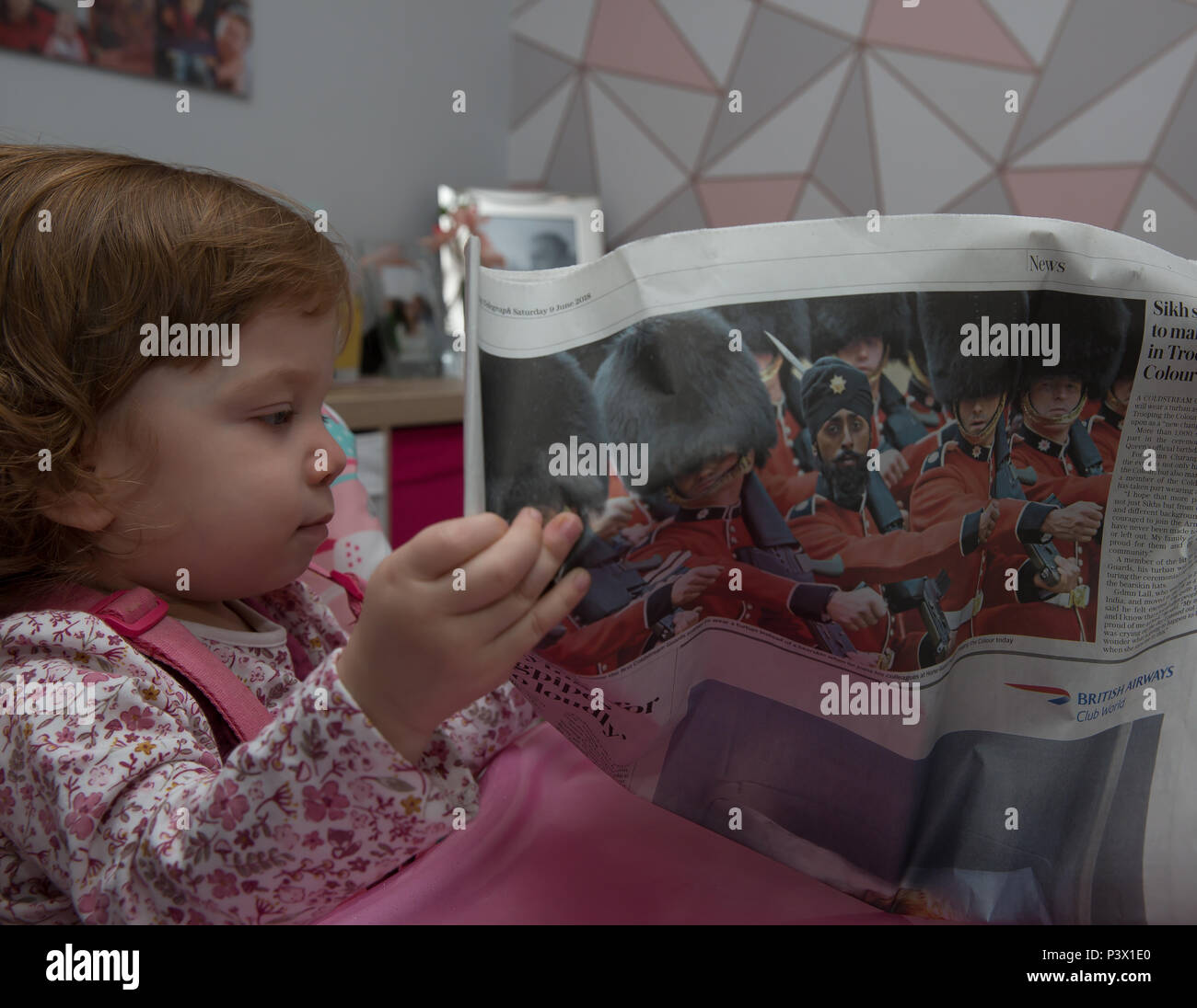 A very young child looks at the Daily Telegraph newspaper while seated ...