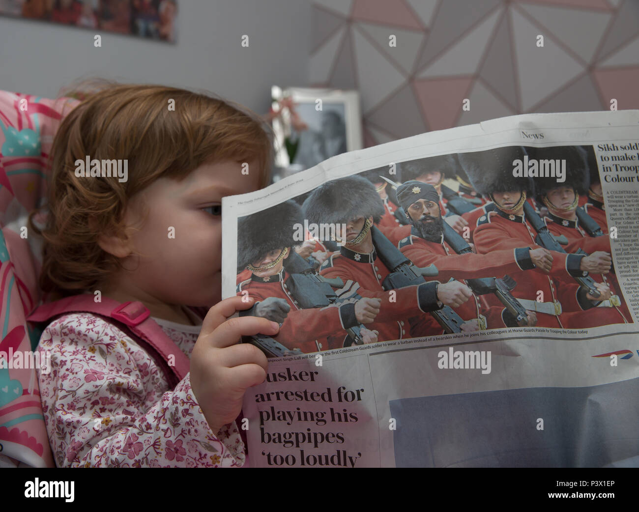 A very young child looks at the Daily Telegraph newspaper while seated ...