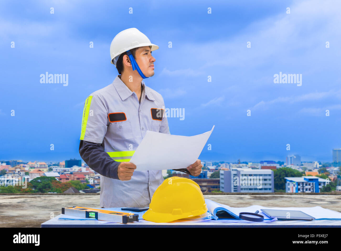 Asian construction engineer holding blueprint at construction site ...