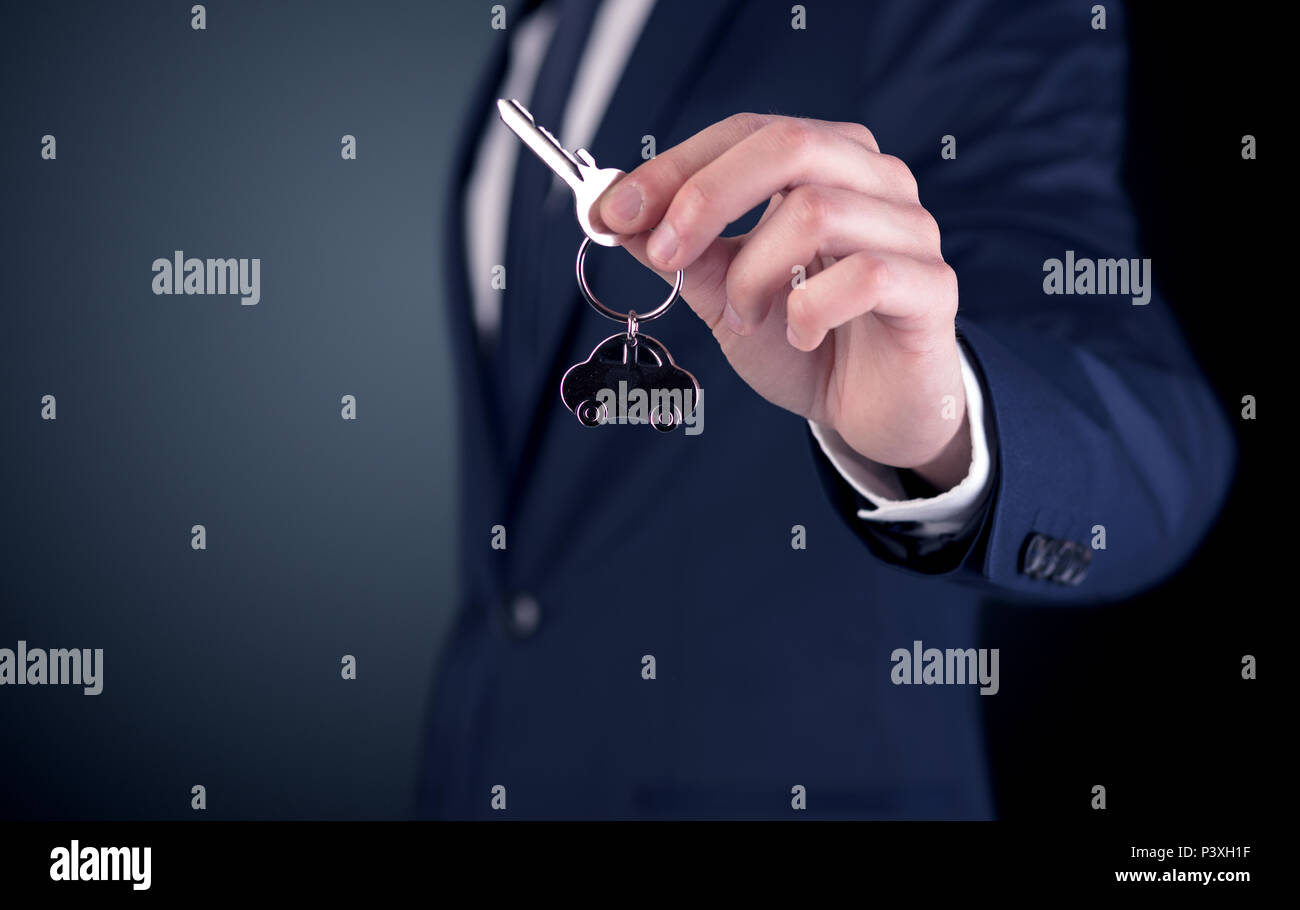 Young businessman hand over keys with empty dark background Stock Photo ...