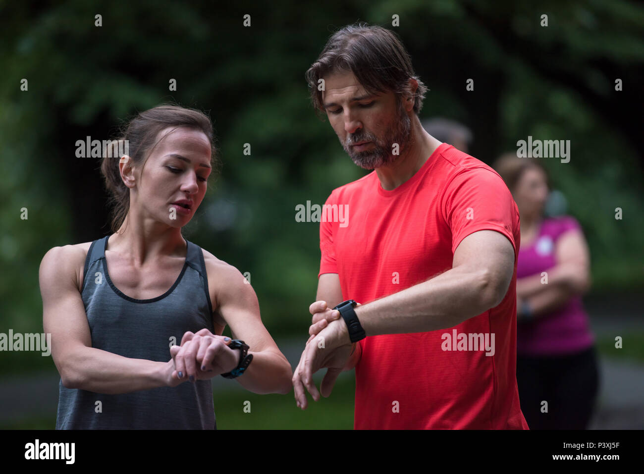 Young sporty couple using smart watches starting their timer before ...