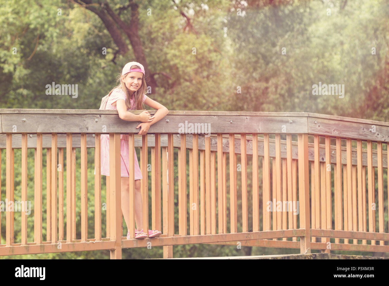Cute little girl standing on a bridge Stock Photo - Alamy