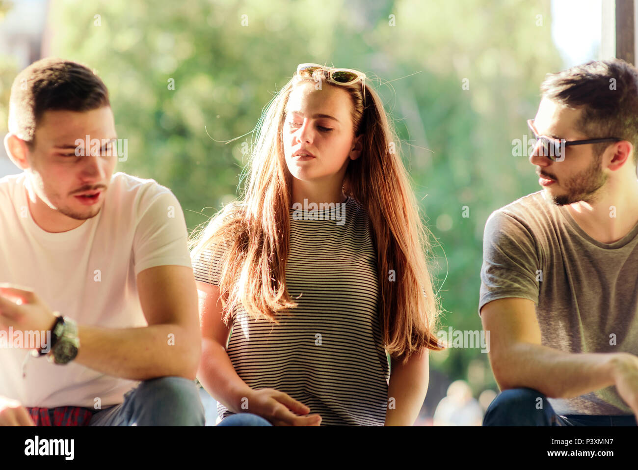 Positive three friends is talking while siiting on the bench Stock ...