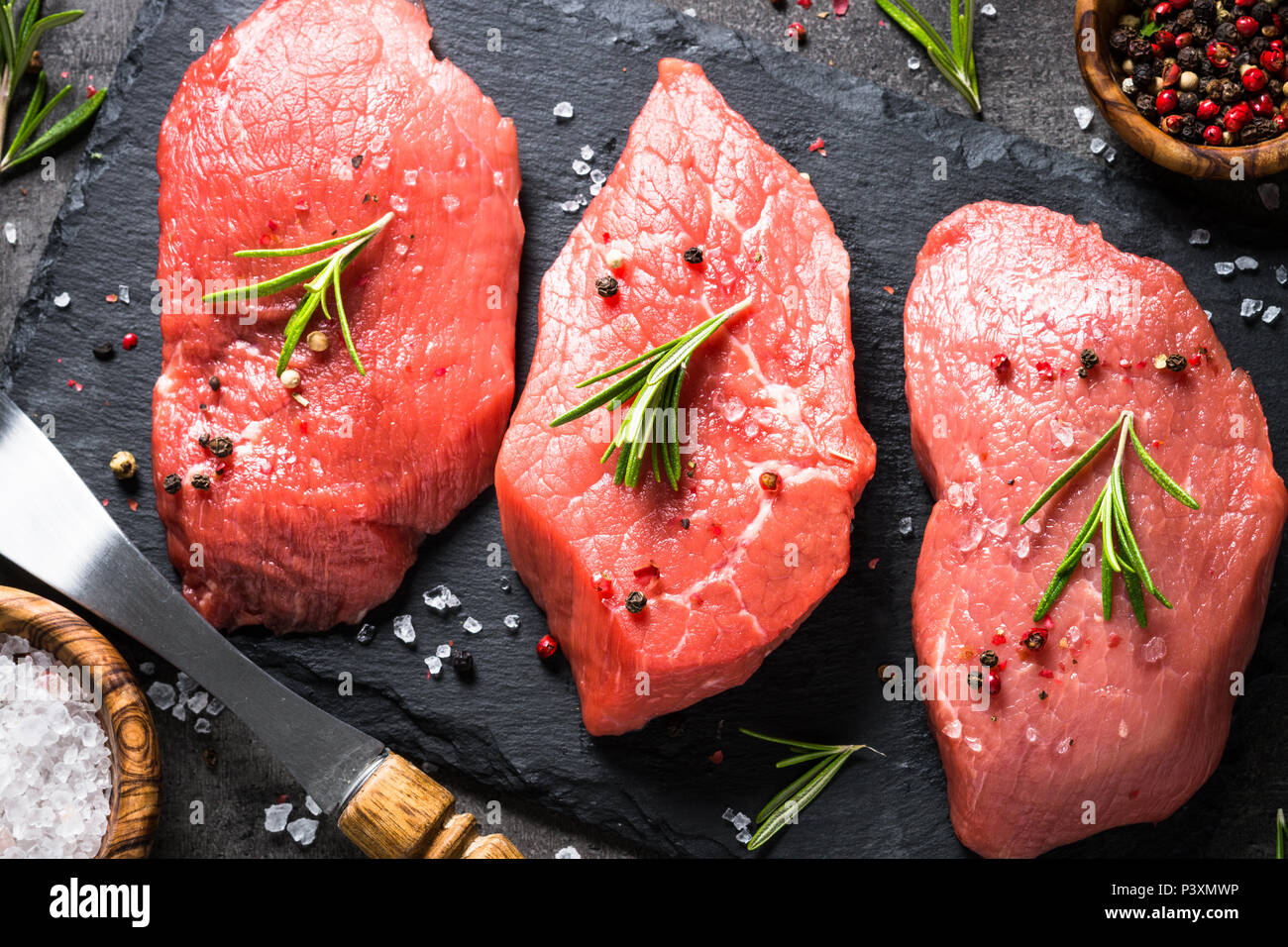 Raw meat. Fresh beef steak with rosemary and spices on black background ...