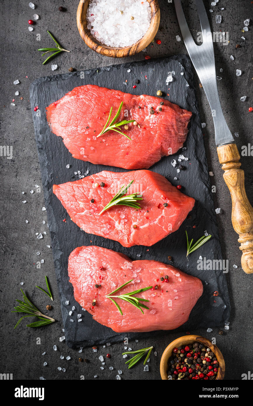 Raw meat. Fresh beef steak with rosemary and spices on black background ...