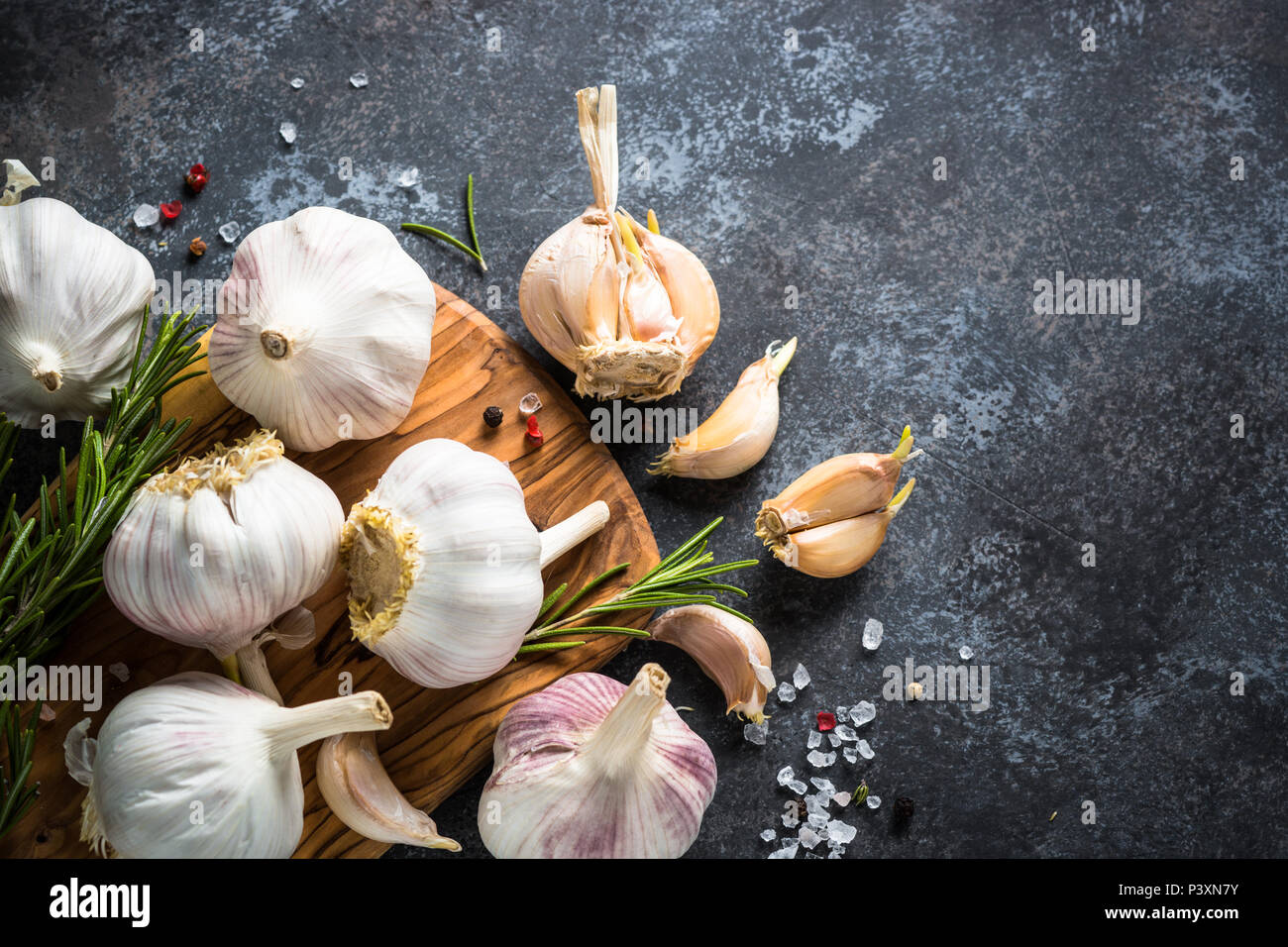 Garlic cloves with spices and herbs on a dark stone background. Top ...