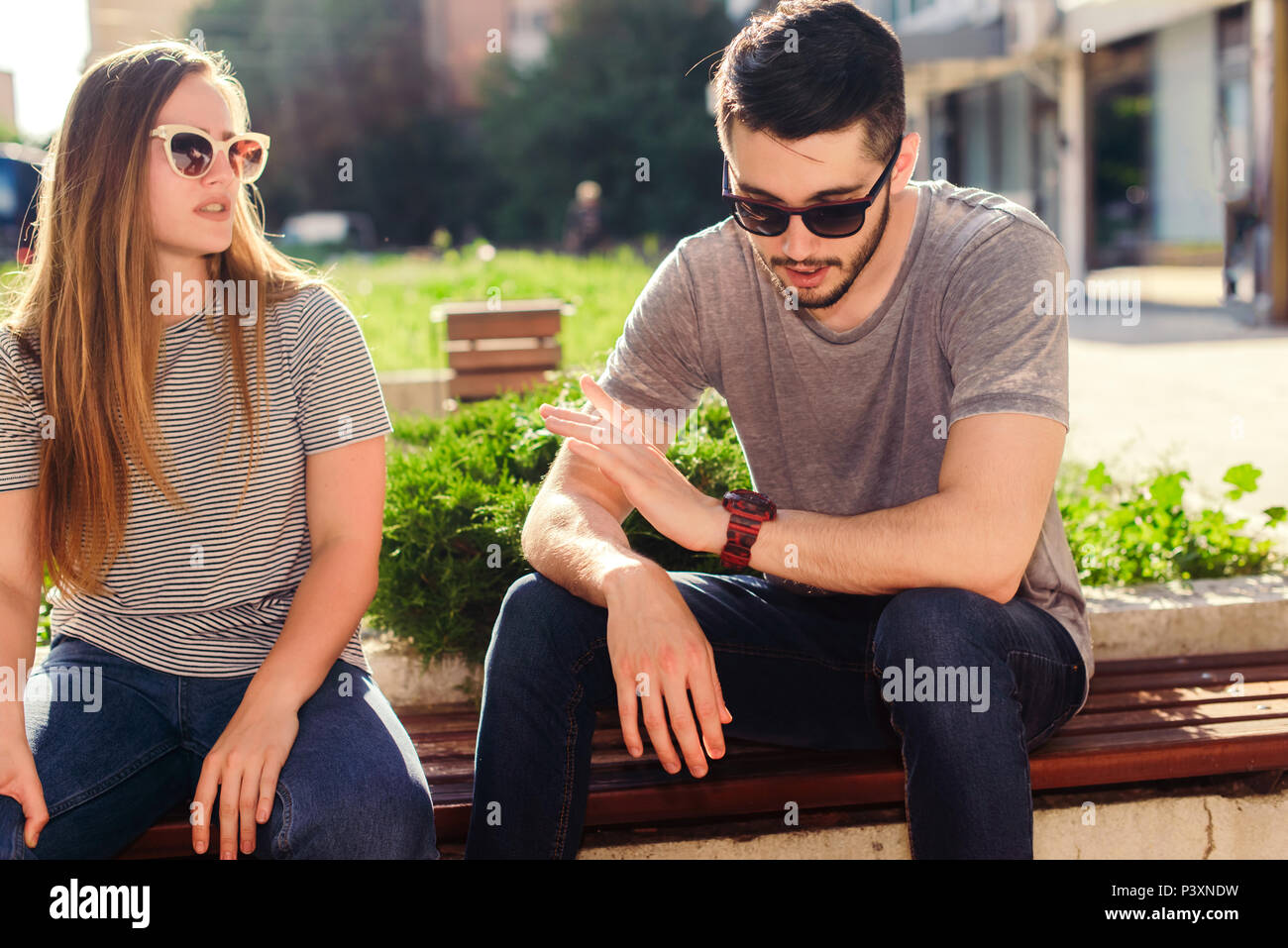 Young happy couple talking each other sitting on bench Stock Photo - Alamy
