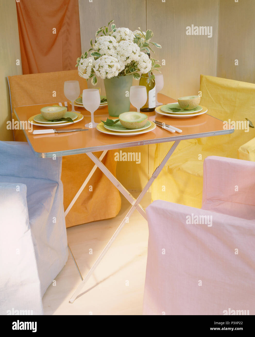 Pastel loose-covers on director's chairs around folding table set for ...