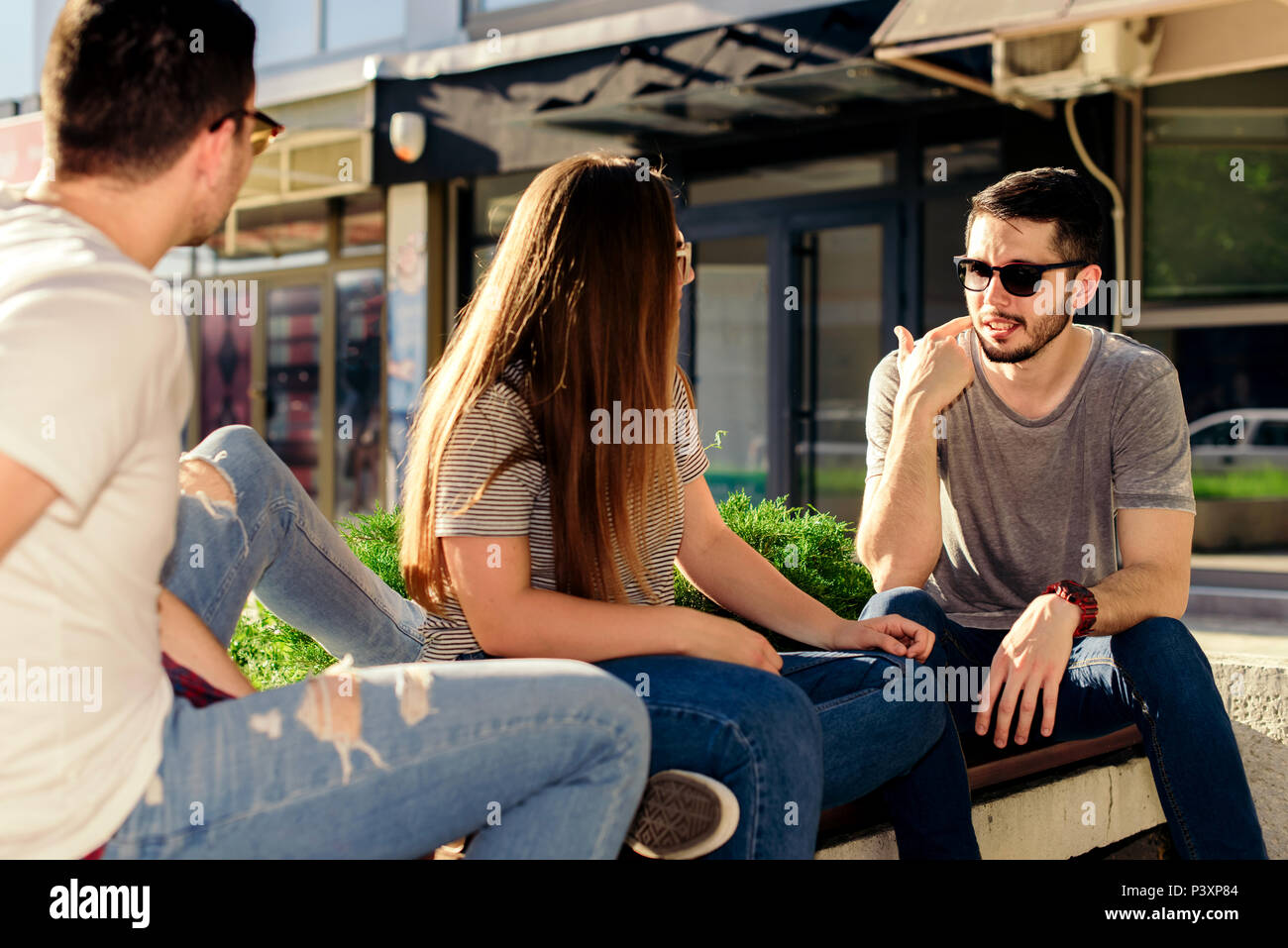 Positive three friends is talking while siiting on the bench Stock ...