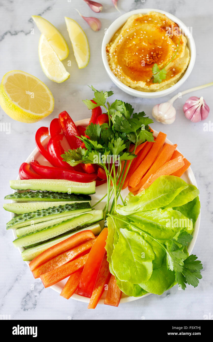 Hummus, different vegetables and lettuce leaves with lemon and garlic ...