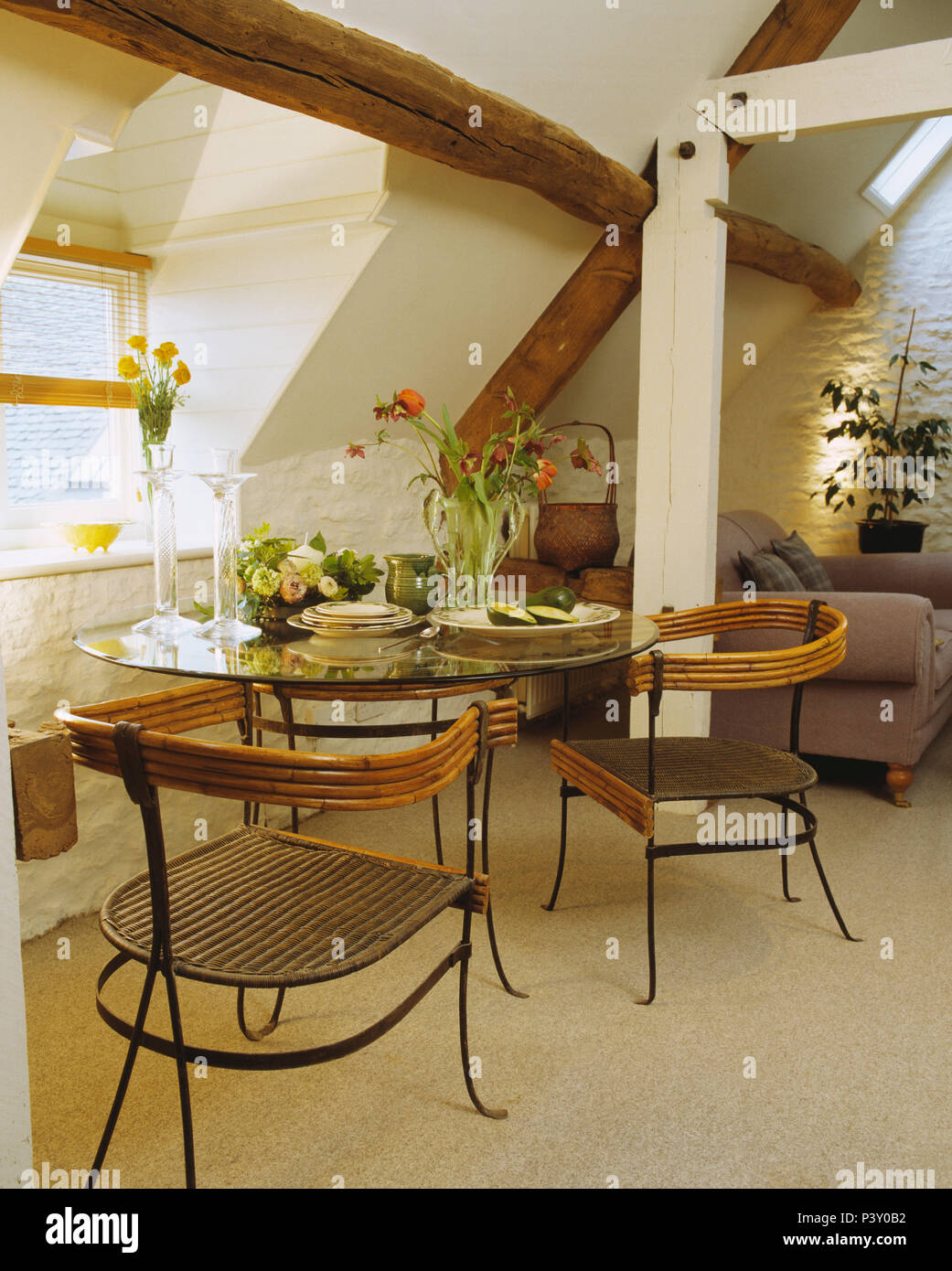 Dining room in open-plan converted stables with cane and metal chairs ...