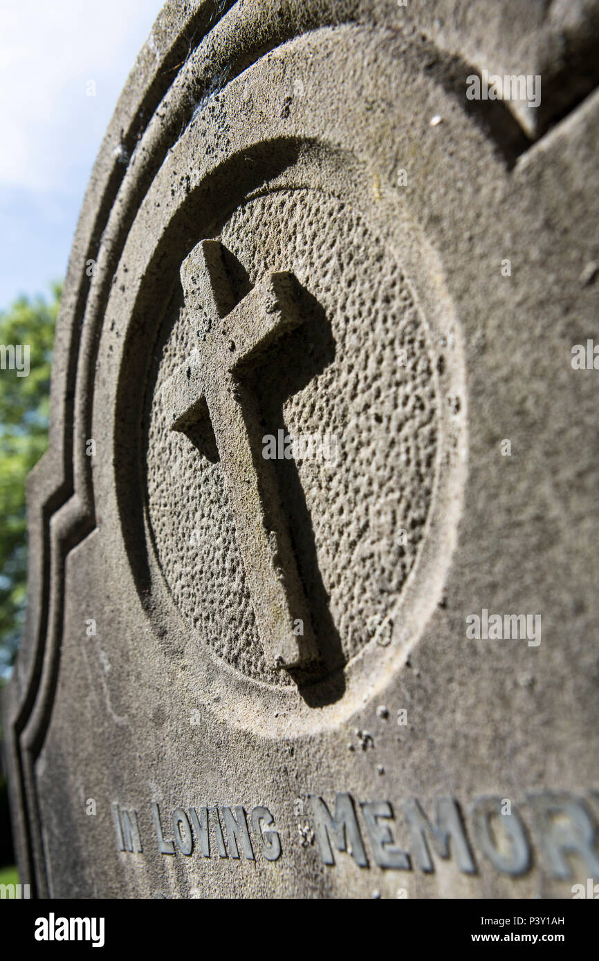 Religious iconography in a summer time, sunlit graveyard headstone on a ...