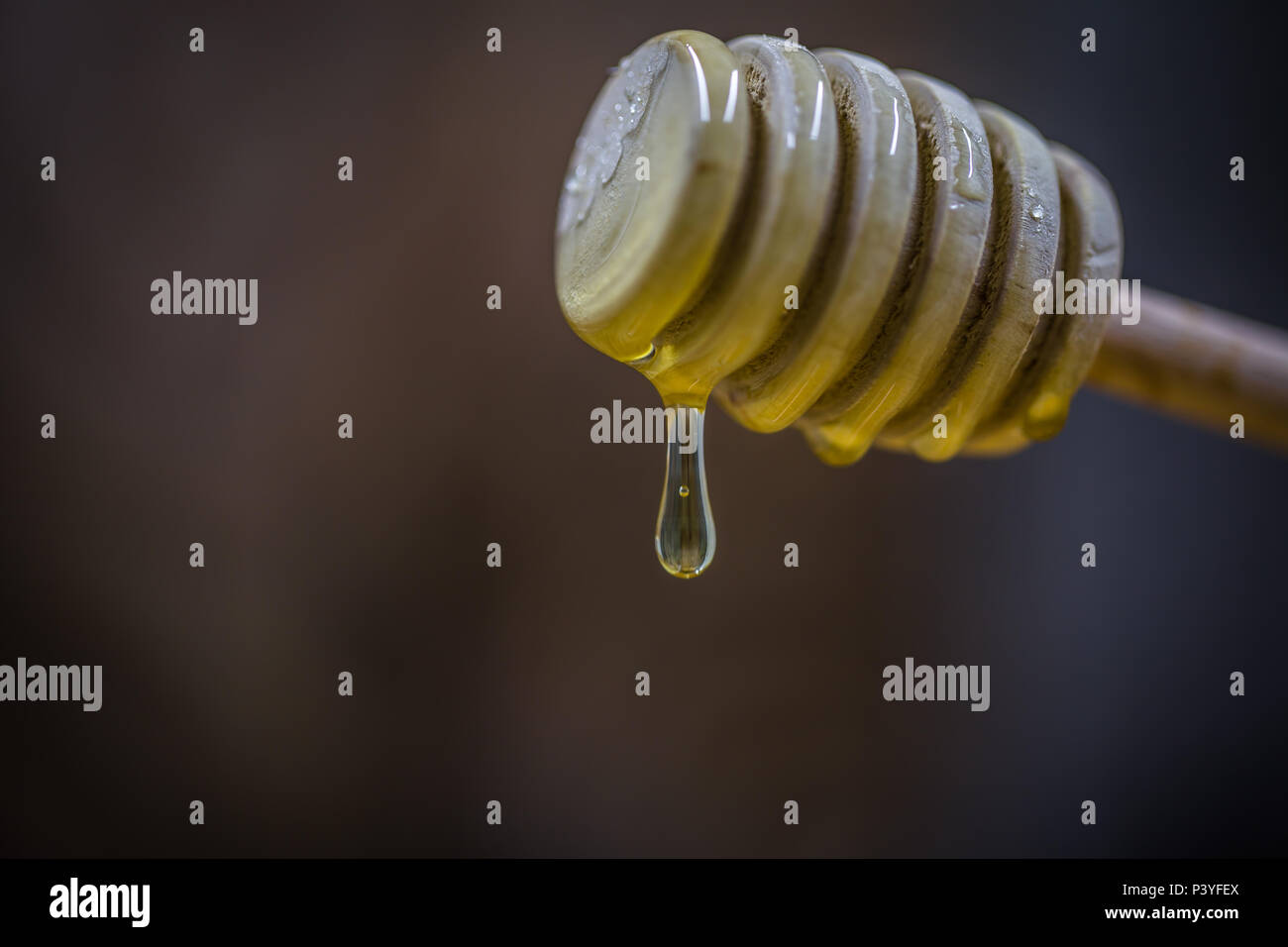 wooden spoon for honey,dripping a drop of honey closeup Stock Photo - Alamy
