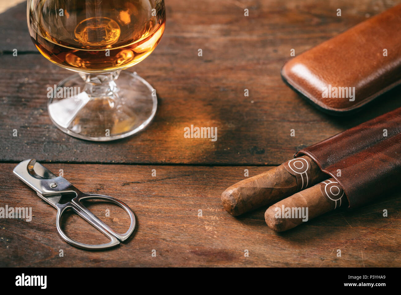Cuban cigars and a glass of cognac brandy on wooden background, closeup ...