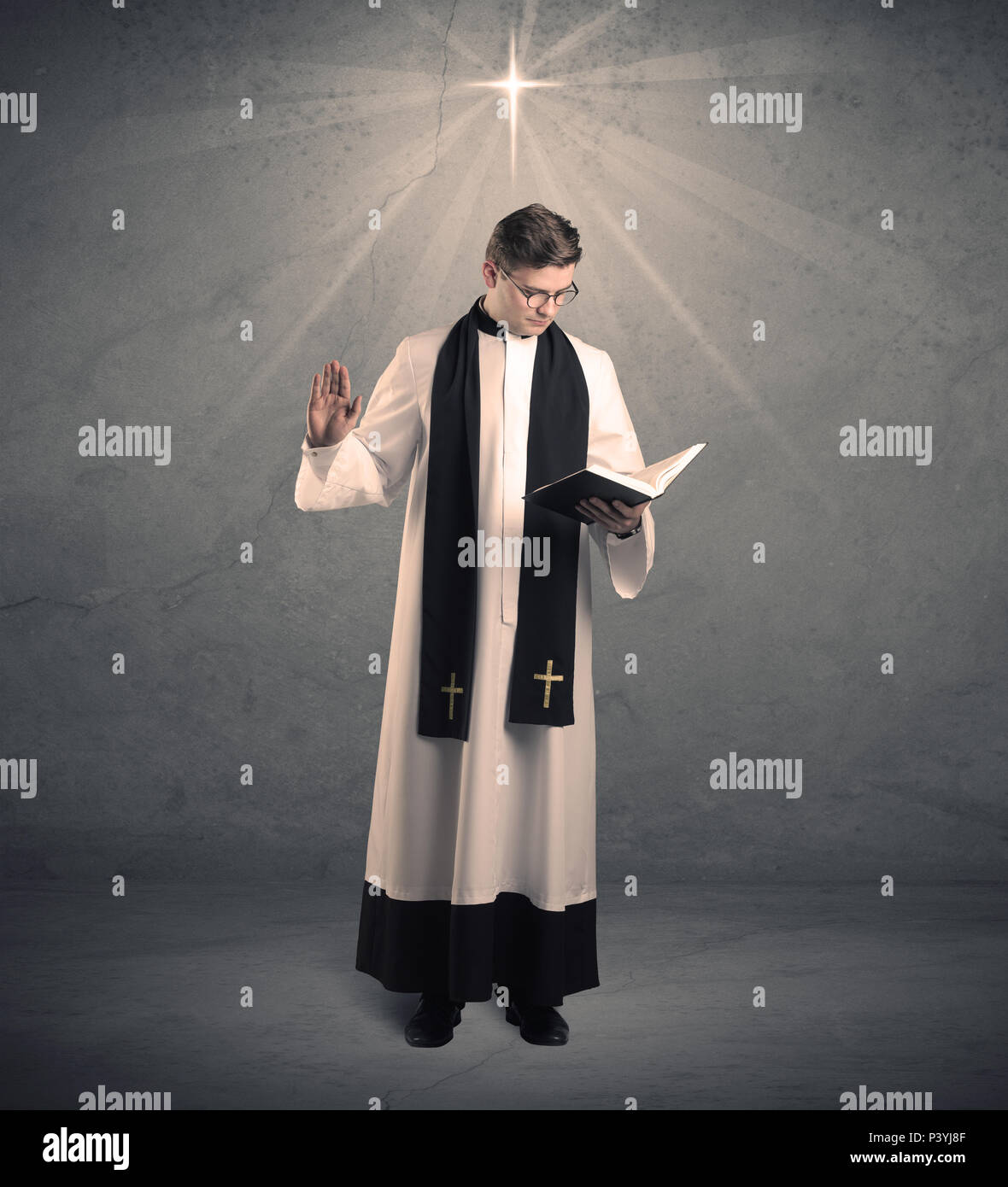 A young male priest in black and white giving his blessing in front of ...