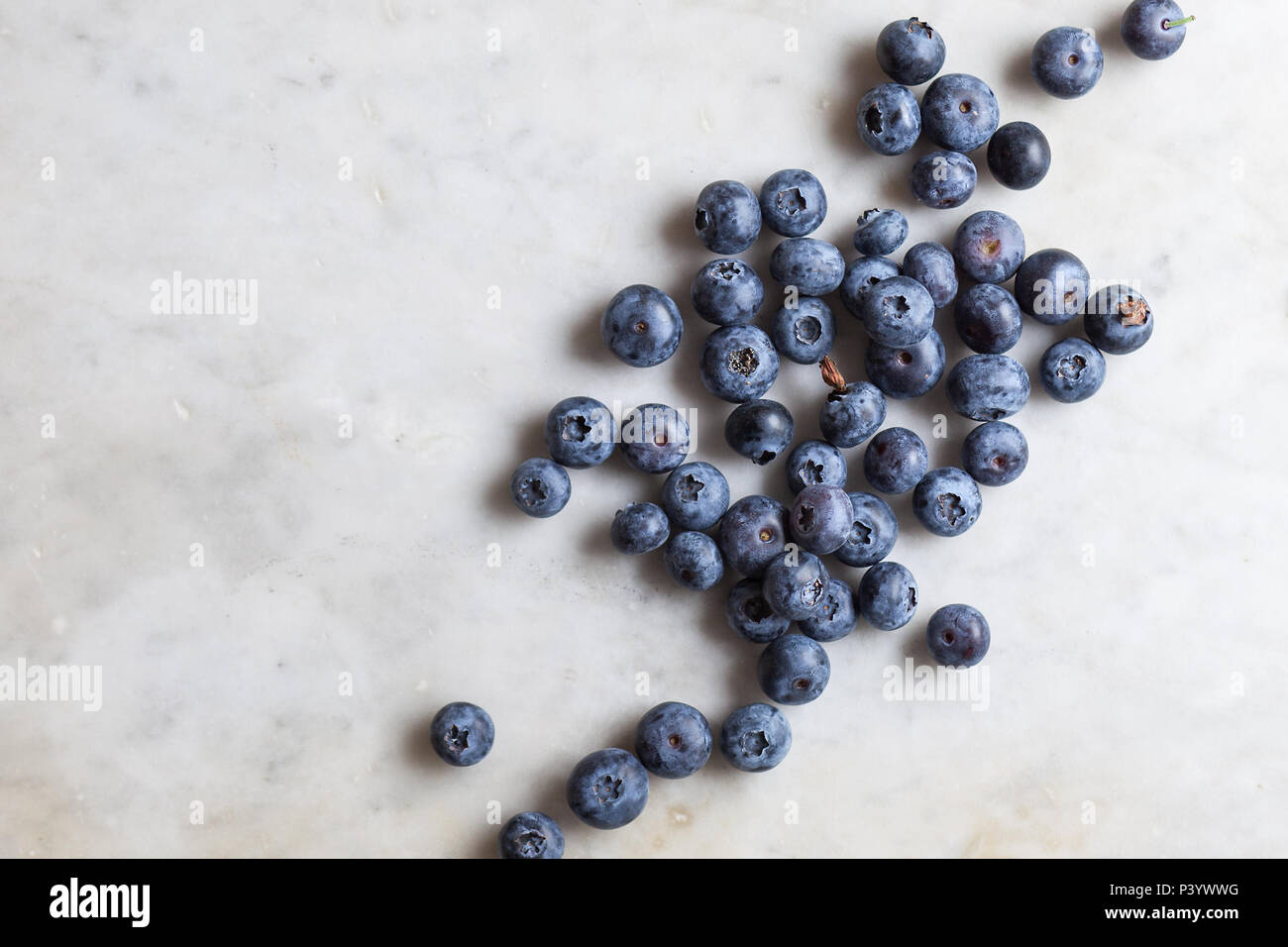 Blueberries scattered on pale grey marble worktop Stock Photo - Alamy