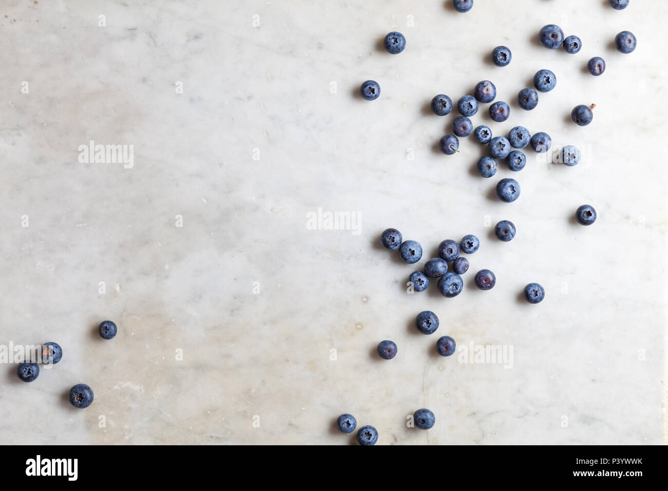 Blueberries scattered on pale grey marble worktop Stock Photo - Alamy