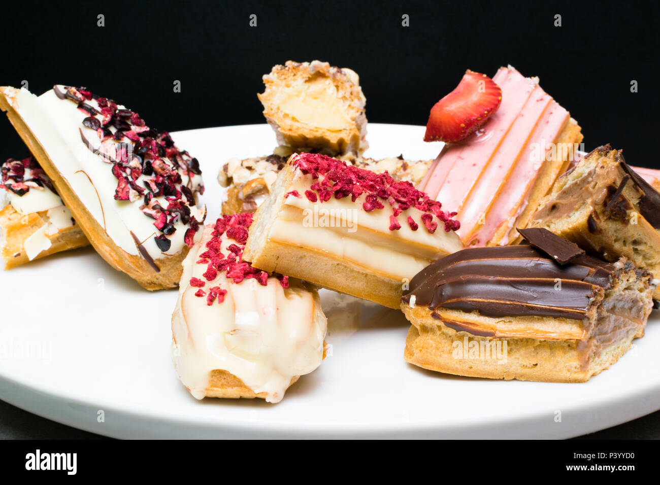 Sweet and colorful french eclairs with berrys, chocolate, nuts. Group ...