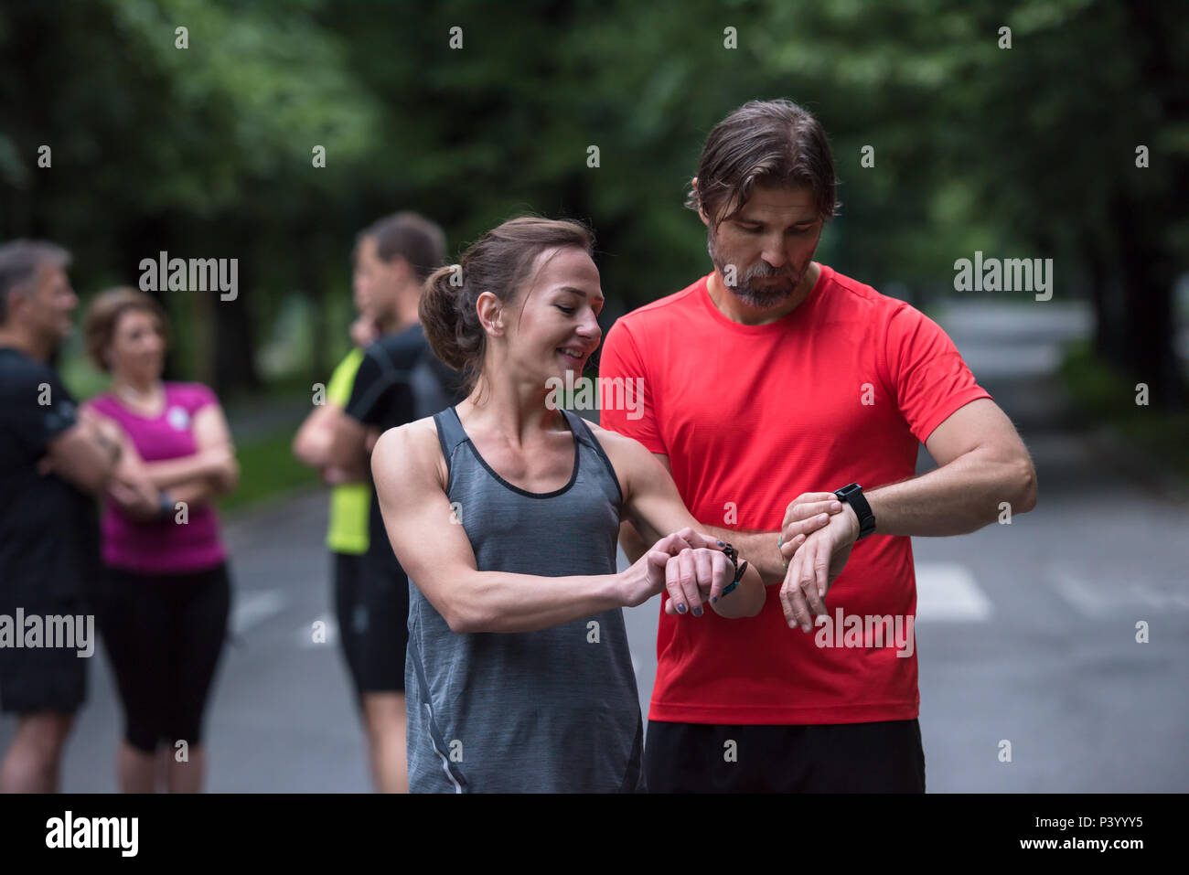 Young sporty couple using smart watches starting their timer before ...