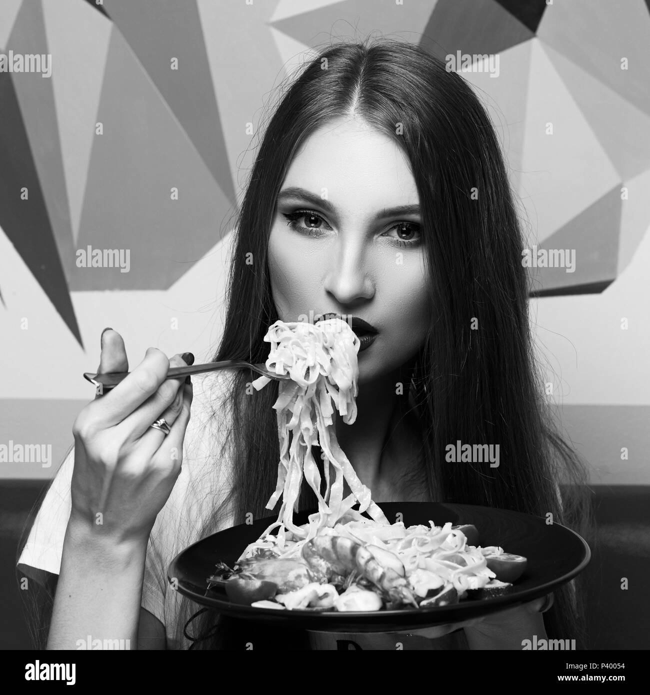 Attractive woman eating seafood pasta Stock Photo - Alamy
