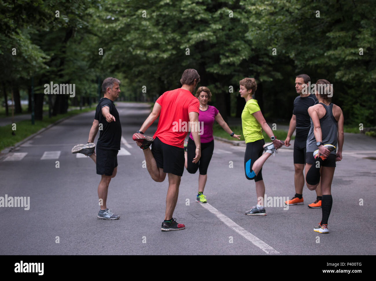 healthy runners team warming up and stretching in city park before ...