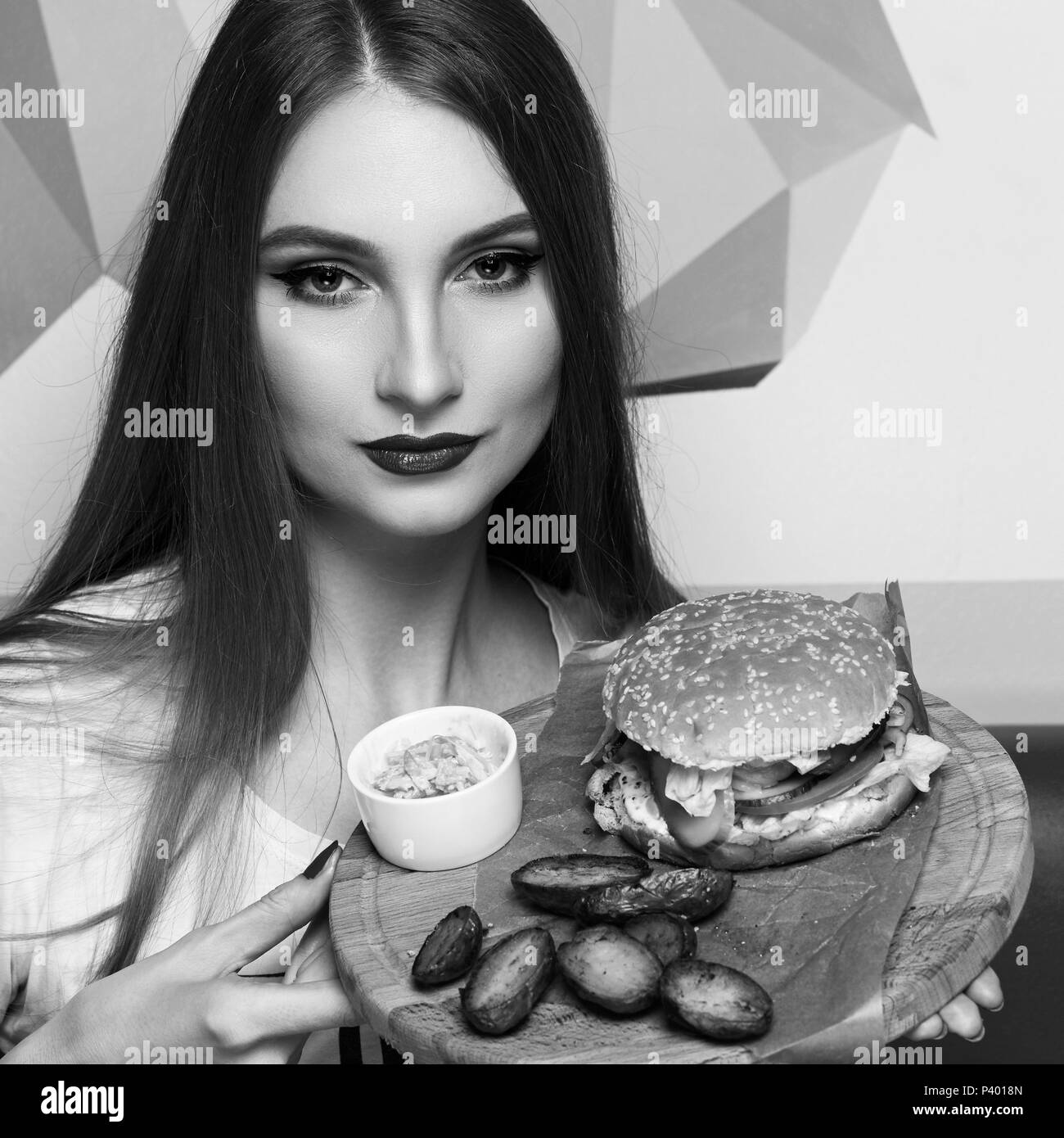 Female model demonstrating burger lying on round wooden plate Stock ...