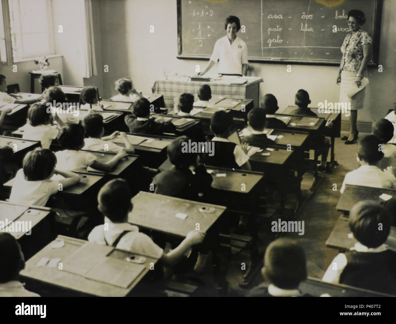Foto de sala de aula da década de 1960, com diretora (direita) e ...