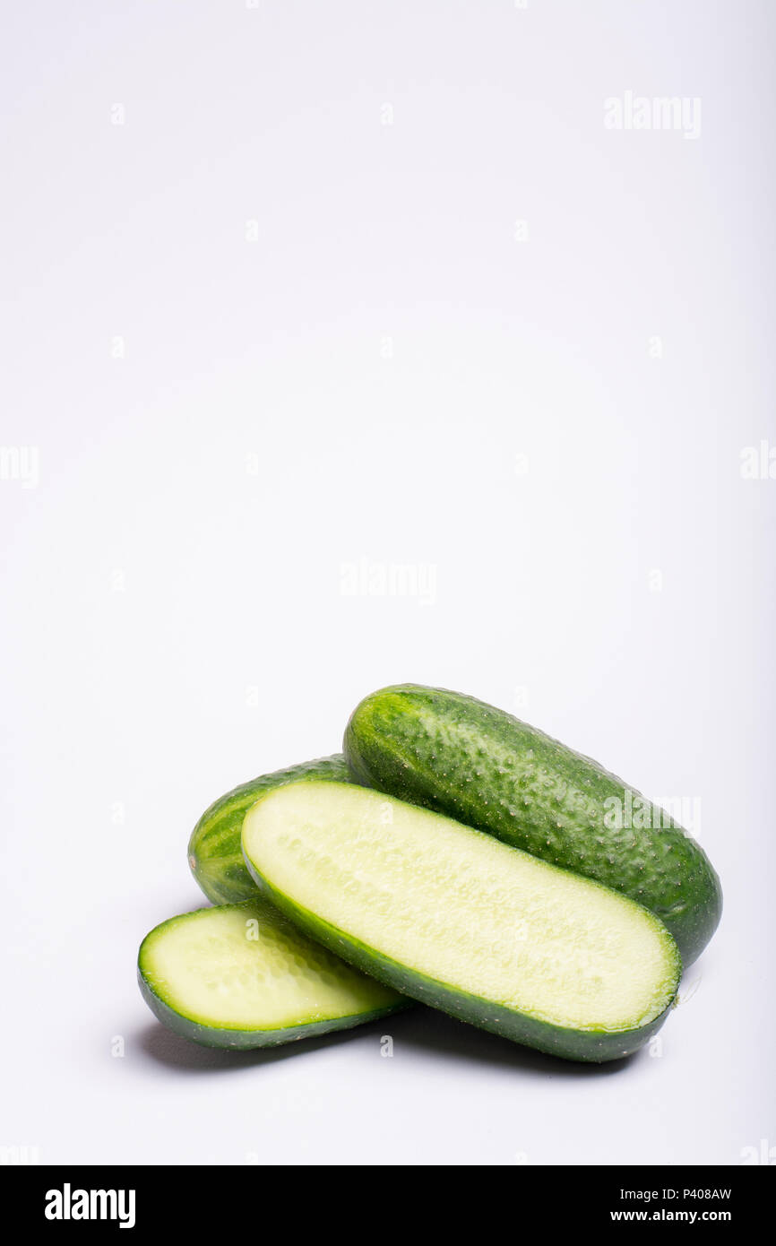 Fresh small green cucumbers whole and sliced close up copy space ...