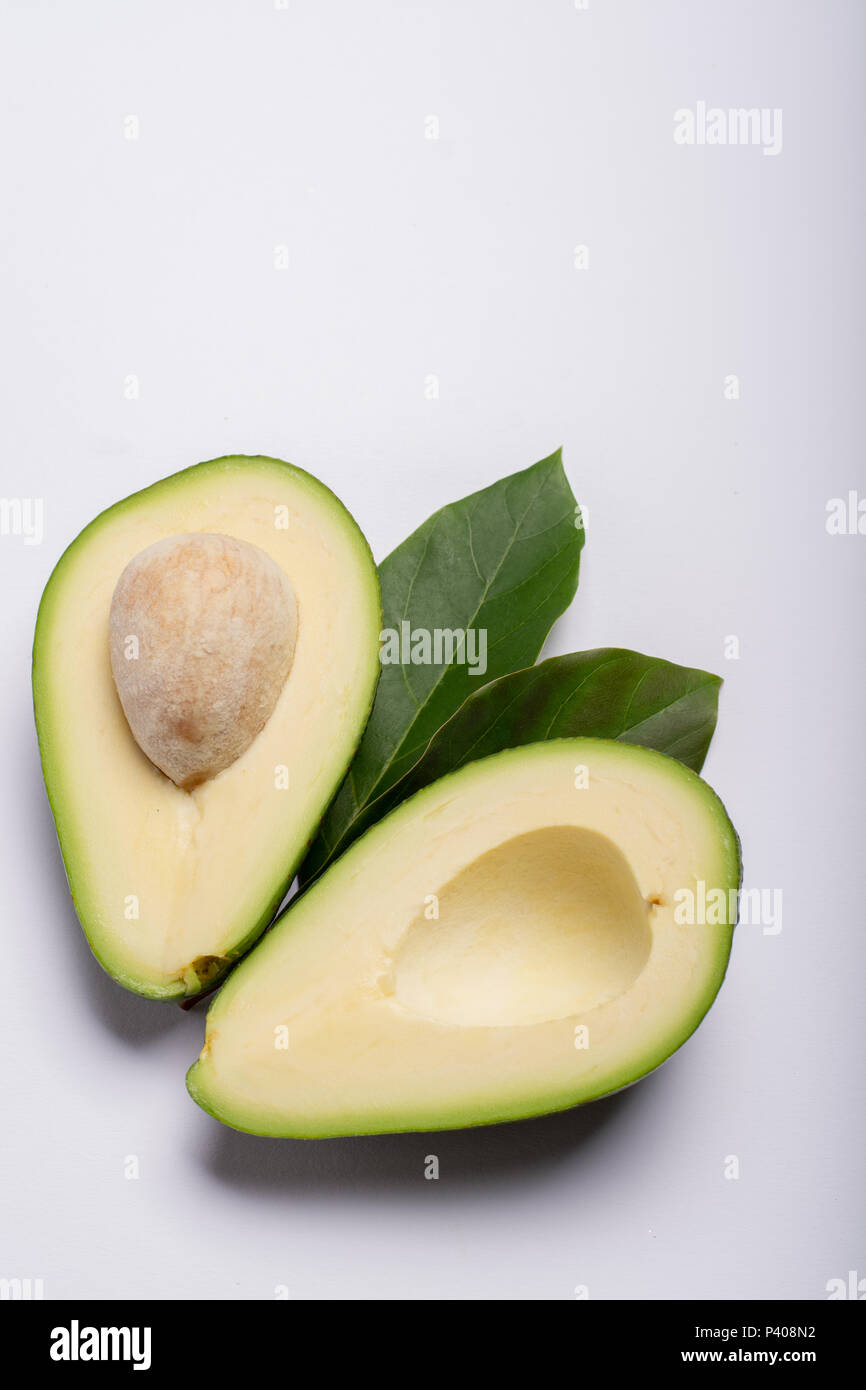 Fresh organic ripe green whole and sliced Fuerte avocado with leaves ...