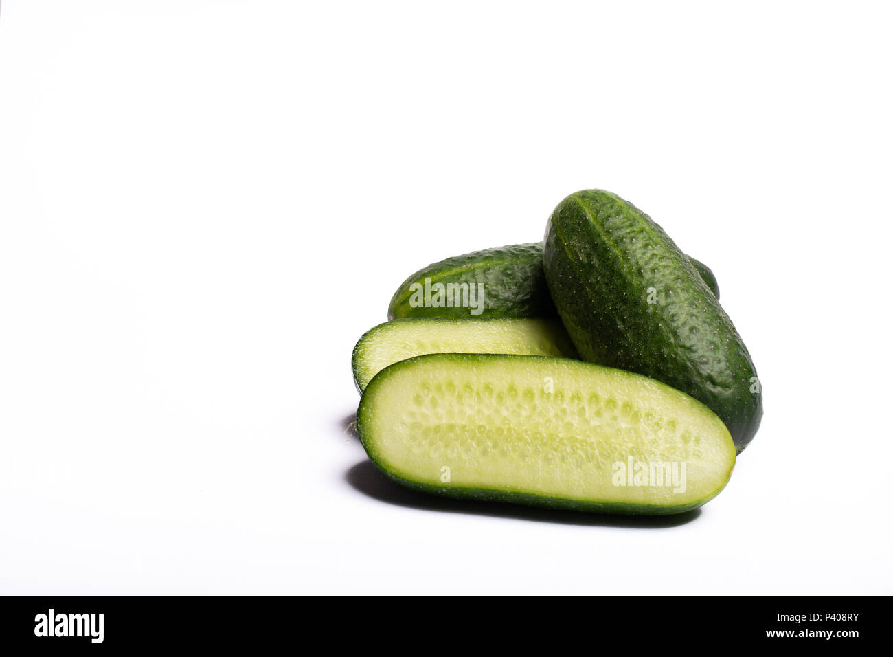 Fresh small green cucumbers whole and sliced close up copy space ...