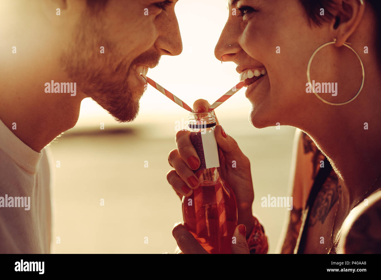 Close up of young couple drinking soft drink with straws from one ...