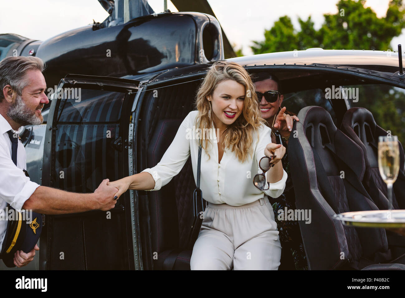 Beautiful young woman disembarking a helicopter with pilot supporting ...