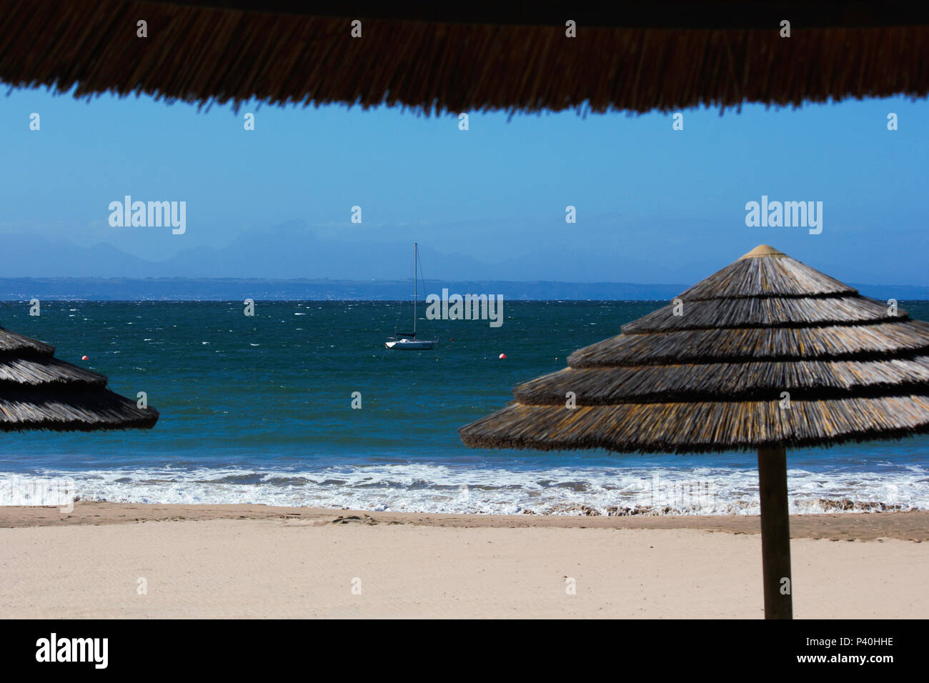 Beach Palapas Overlooking Ocean With Sailboat Stock Photo - Alamy
